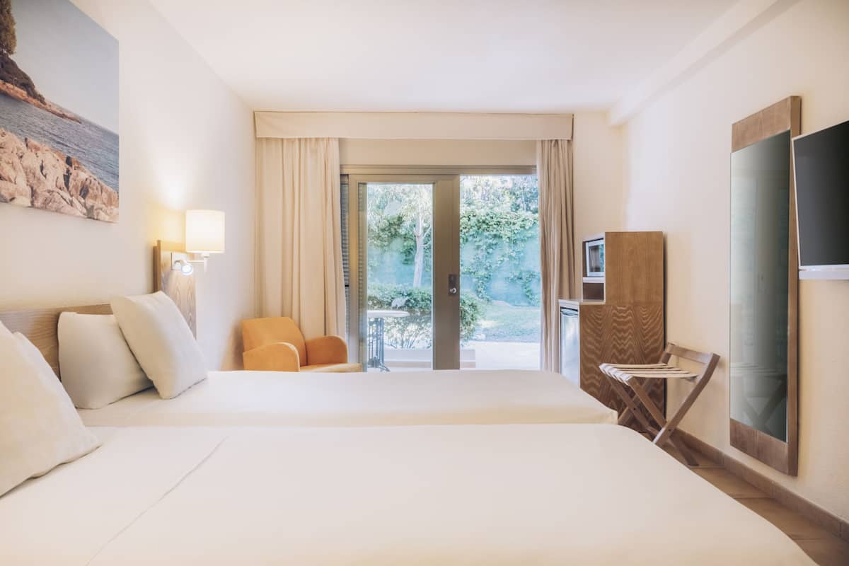 Quarto de hotel com uma cama grande, um sofá, uma TV e vista para o exterior.