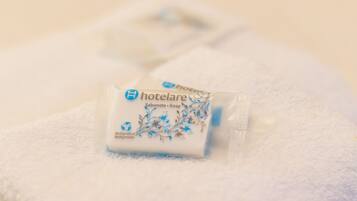 Embalagem de produtos de higiene de hotel com a etiqueta 'hotelare' sobre uma toalha branca.