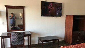 Quarto de hotel com uma cama, uma mesa, uma cadeira, uma televisão e um guarda-roupa.