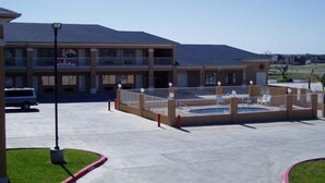 Um hotel com área de piscina, estacionamento e um edifício com várias varandas.