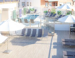 Área de piscina no terraço com espreguiçadeiras e guarda-sóis, uma piscina e uma escadaria que leva a um andar superior.