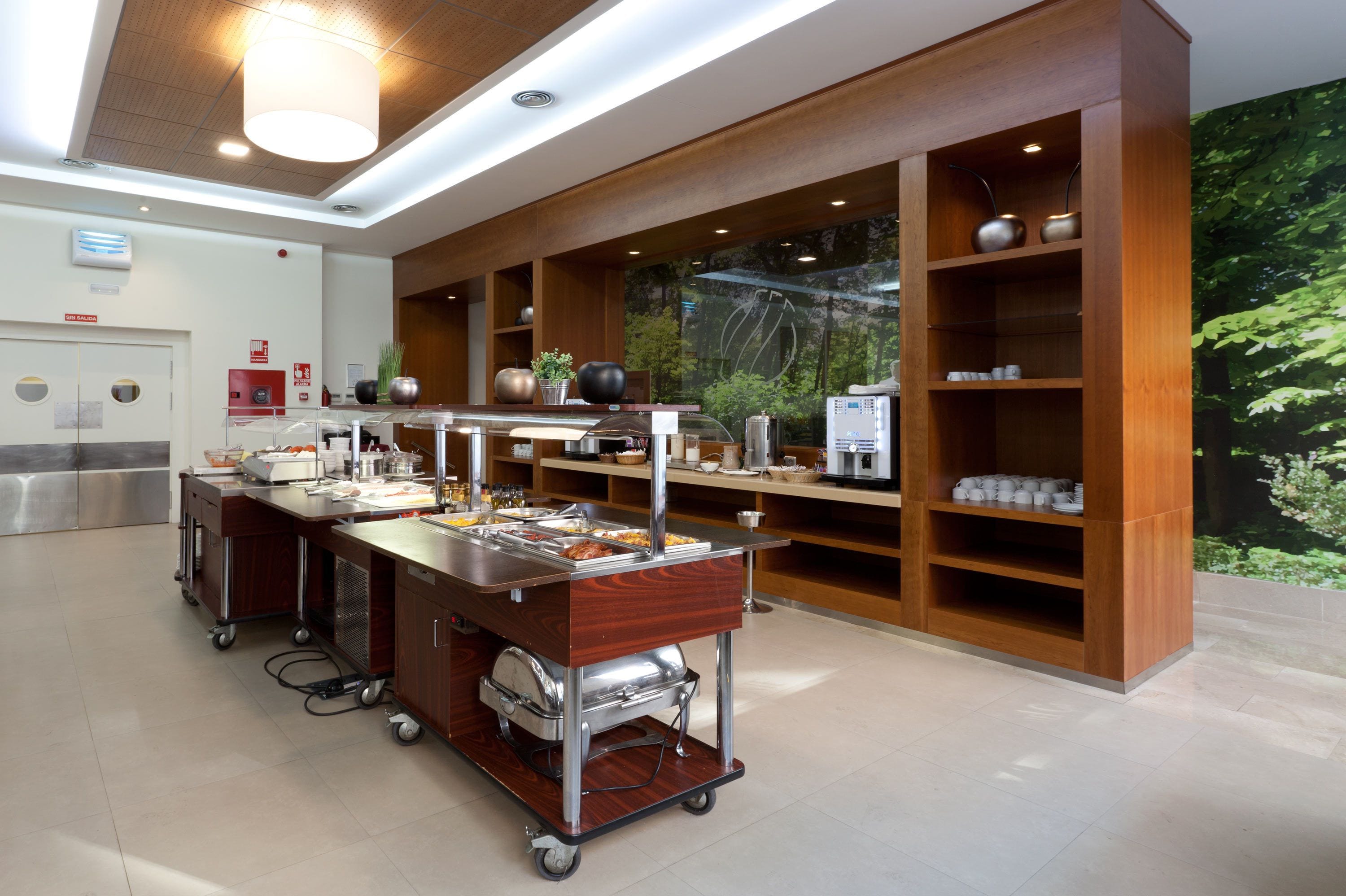 Disposição de buffet com carrinho de comida, mesa de buffet e prateleiras com louças.