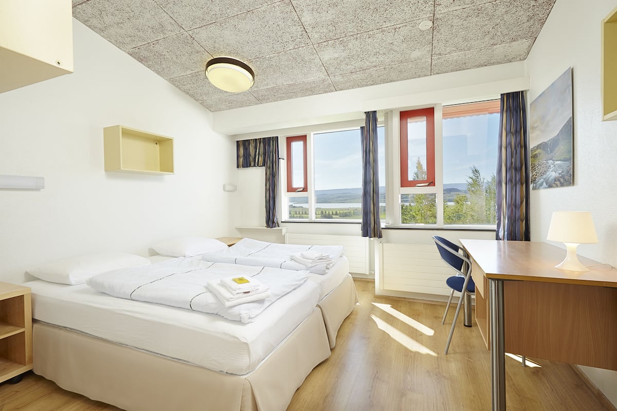 Quarto de hotel com uma cama grande, uma escrivaninha e vista para o exterior.