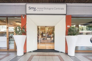 Entrada do Hotel S.M.Y Bologna Centrale, com design moderno, fachada de vidro e uma entrada convidativa.