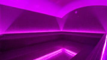 Um spa moderno com design geométrico em azulejos e iluminação roxa.
