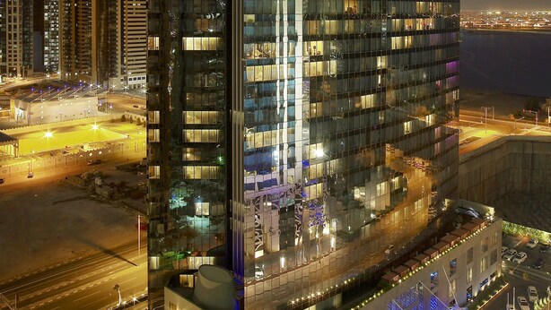 Um hotel moderno e imponente, com design angular característico, vários andares e vista para a orla marítima.