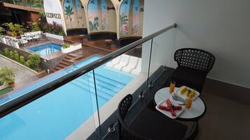 Uma varanda com vista para a piscina, uma mesa com comida e um letreiro com a inscrição "IZIPIZZA".