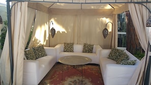 Uma área de estar acolhedora com um sofá branco, uma mesa redonda pequena e arandelas decorativas.