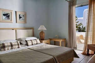 Quarto de hotel com duas camas, uma mesa de cabeceira, um abajur e vista para o exterior.