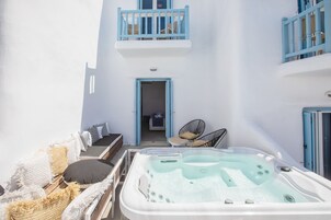 Área de spa com hidromassagem, mobiliário de vime e varanda com guarda-corpos azuis.
