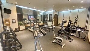 Uma academia com máquinas de cardio, equipamentos de musculação e espelhos nas paredes.