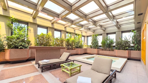 Espaço lounge moderno com assentos, piscina e vegetação.