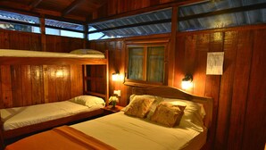 Uma cabana de madeira com duas beliches, uma janela com vista e uma porta de madeira com um aviso.