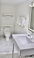 Casa de banho moderna com lavatório branco, sanita e porta-toalhas.