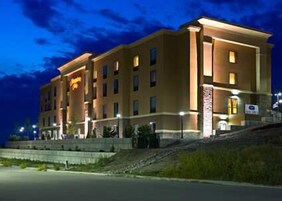 Um hotel com vários andares, fachada plana, várias janelas e uma entrada bem iluminada.