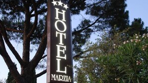 Placa de hotel com o nome 'HOTEL MARZIA' e três estrelas.