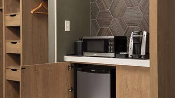 Uma cozinha compacta com micro-ondas, máquina de café e lava-louças.
