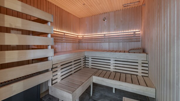 Uma sauna com bancos de madeira, teto inclinado e uma pequena janela redonda.