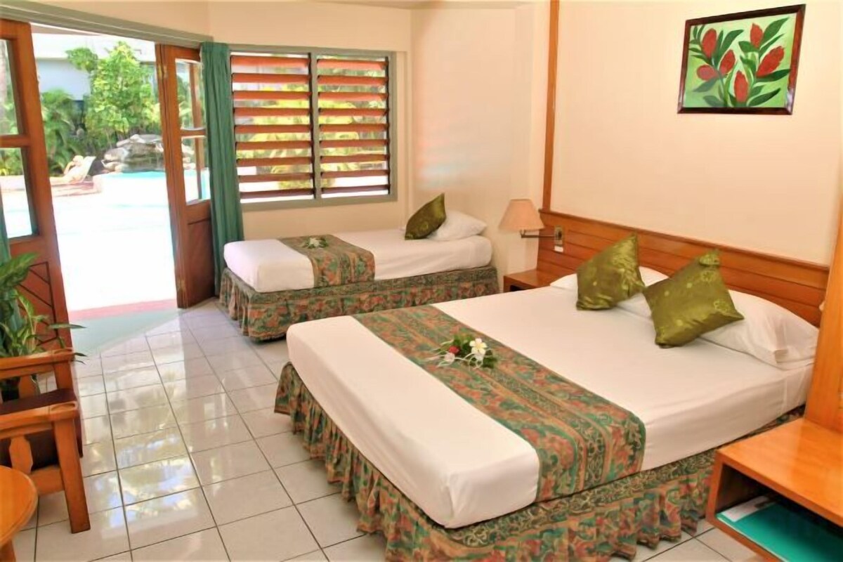 Quarto de hotel com duas camas, uma escrivaninha e uma cadeira.
