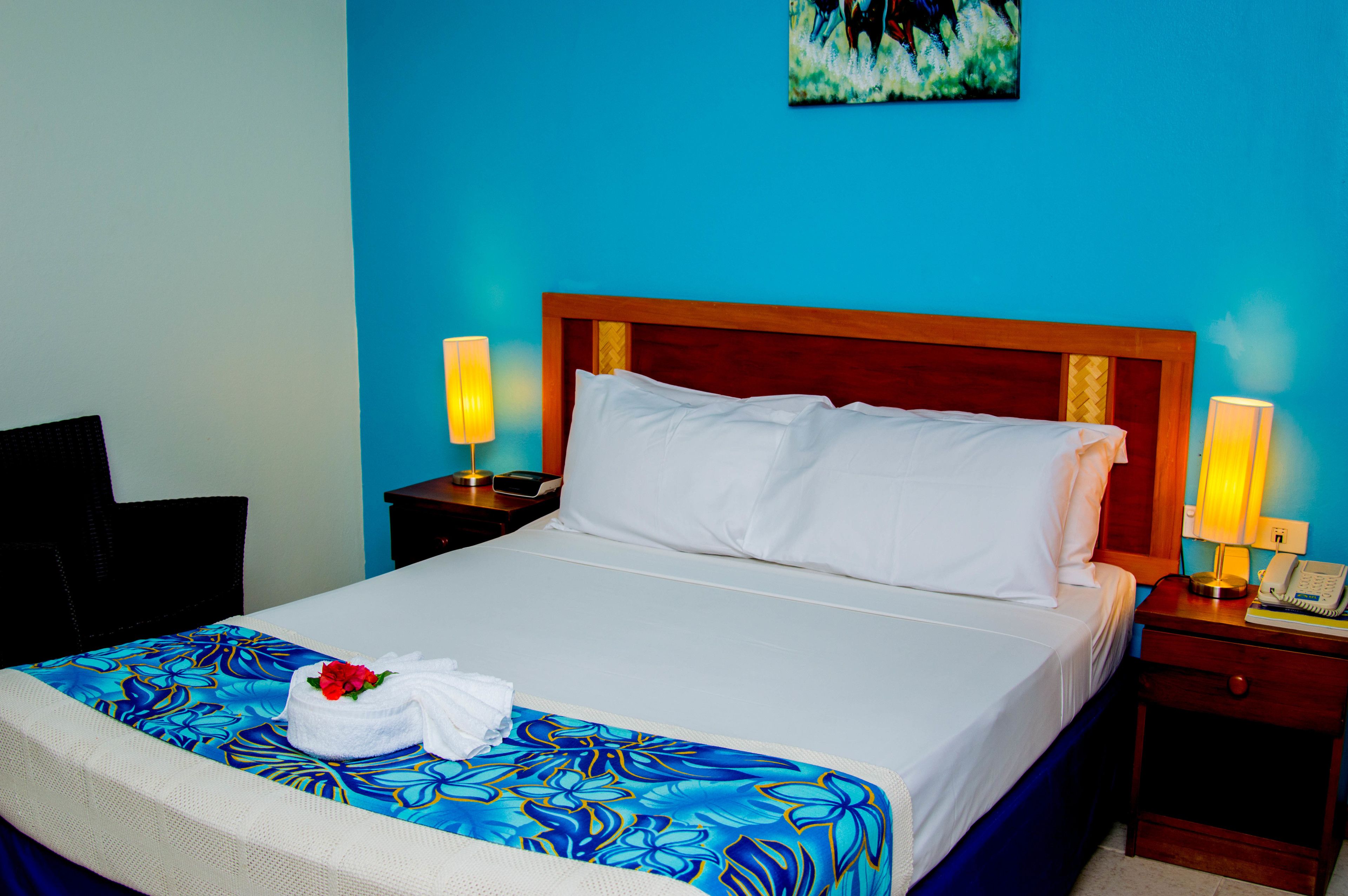 Quarto de hotel com cama, mesas de cabeceira e um quadro na parede.