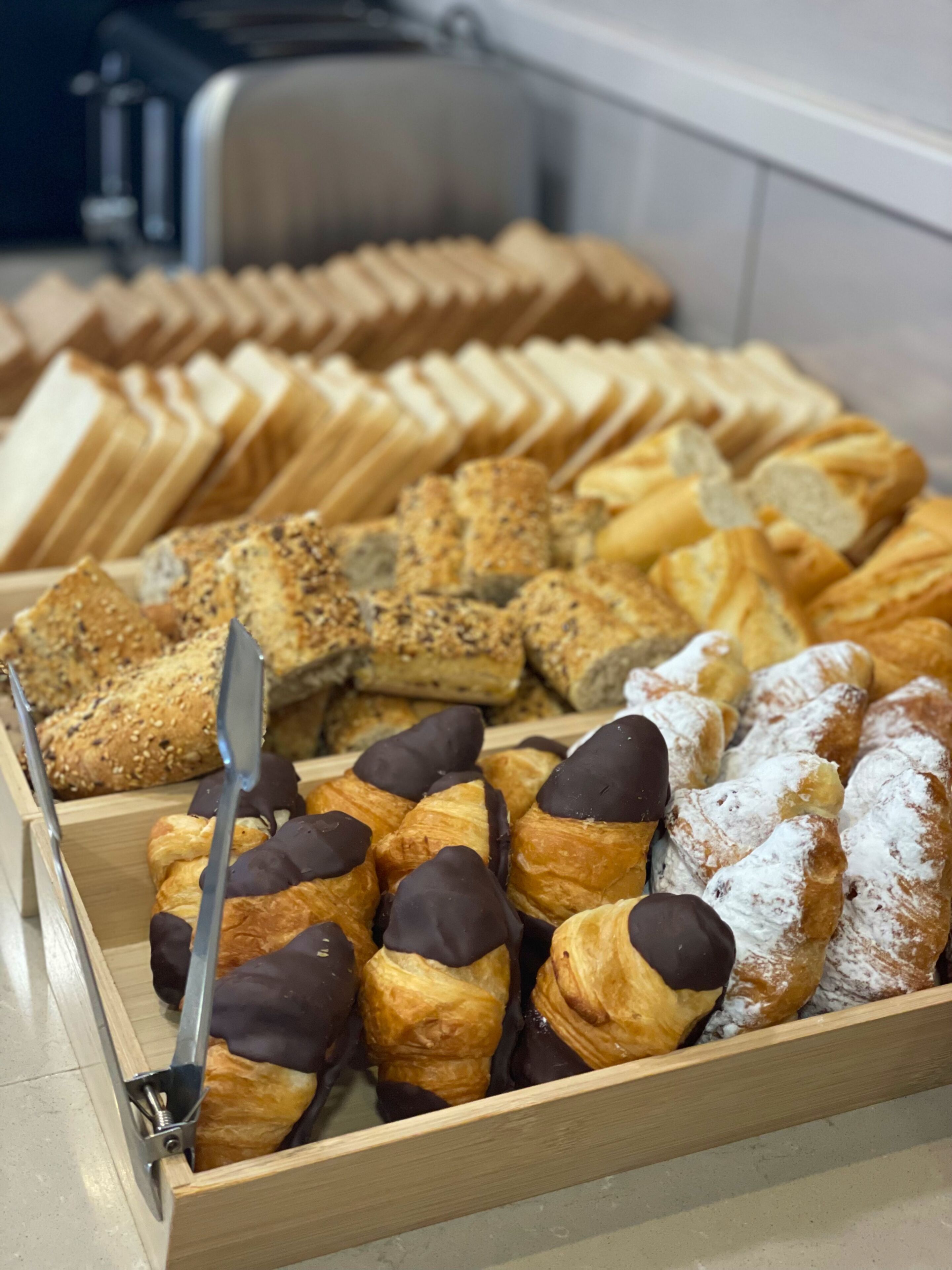 Diversos pães e doces em vitrine de madeira.