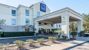 Edifício do Sleep Inn & Suites com entrada visível, área de espera coberta e estacionamento.