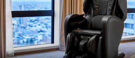 Uma cadeira de massagem num quarto com uma grande janela com vista para a paisagem urbana.