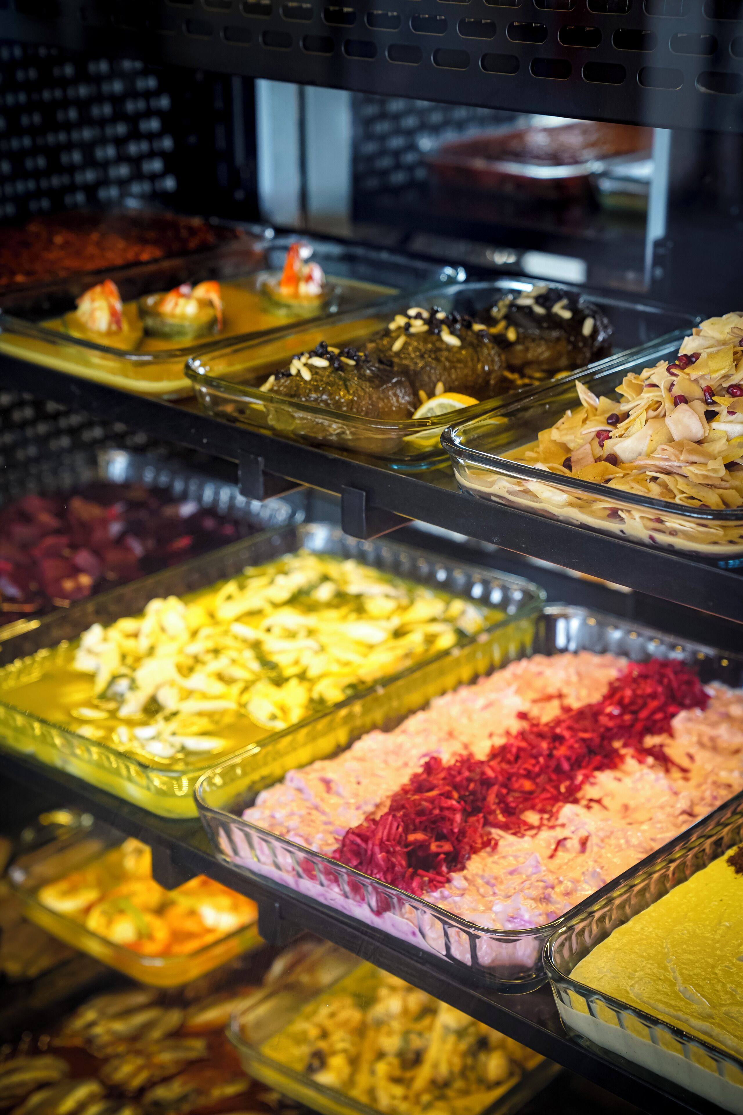 Buffet com diversos pratos em recipientes de vidro.