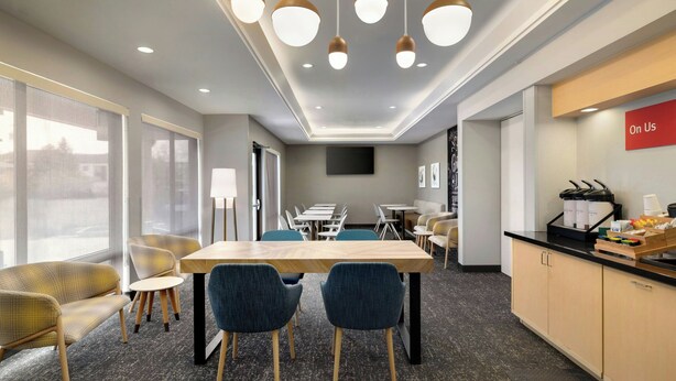 Uma sala de reuniões moderna com uma mesa comprida, cadeiras e luminárias pendentes.