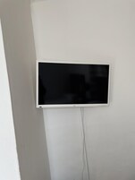 Televisão de tela plana presa em parede branca.