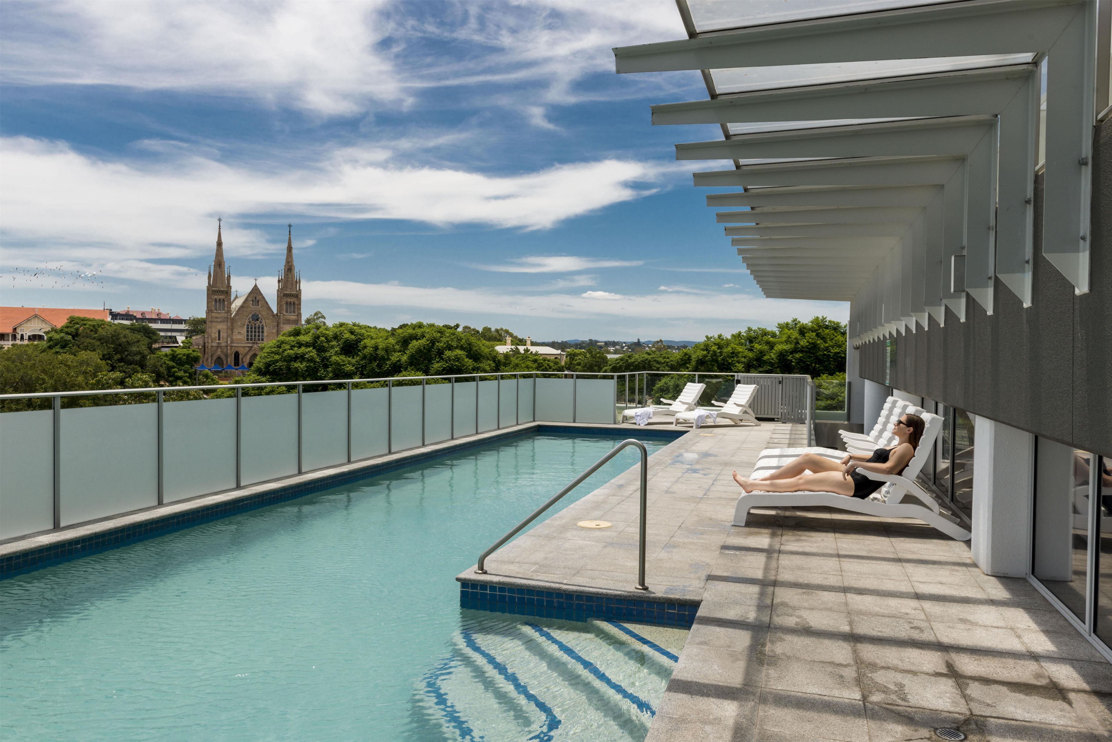 Piscina no terraço com vista para uma igreja e vegetação.