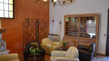 Um quarto com poltronas de couro, um armário de madeira com garrafas e um painel decorativo de ferro.