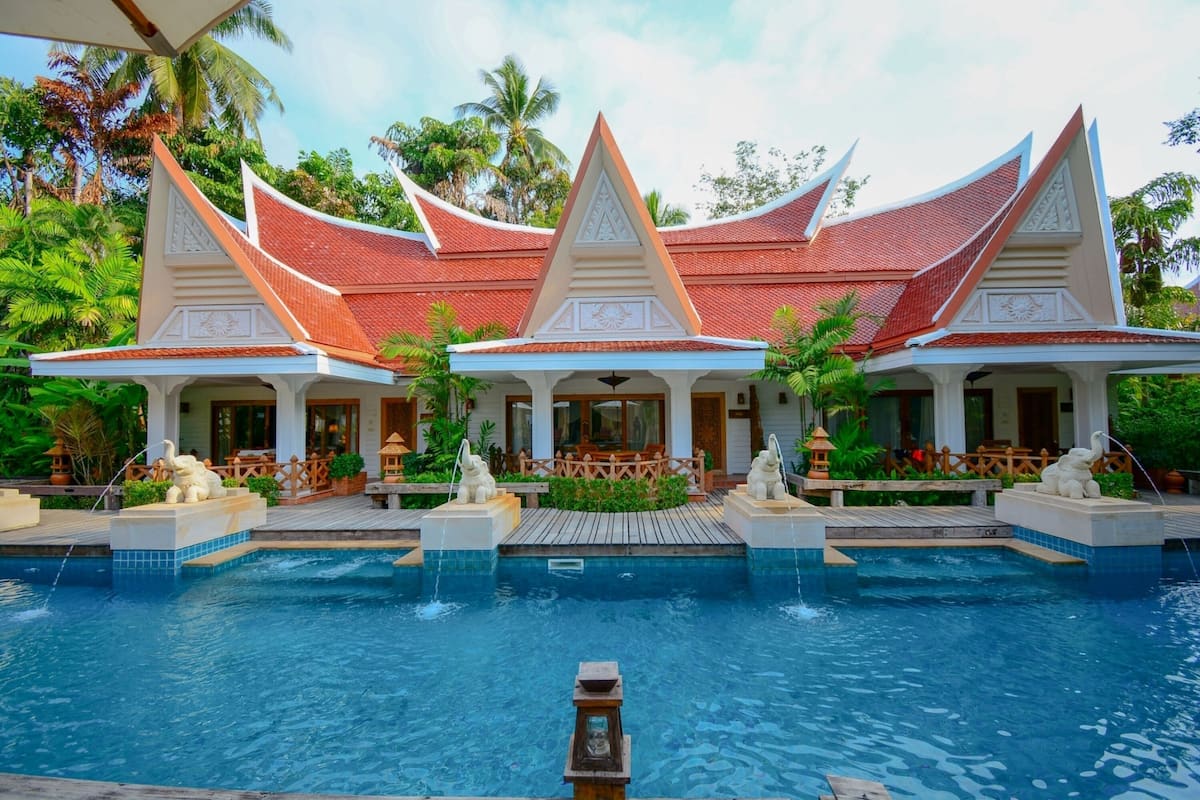 Um edifício em estilo tailandês tradicional com uma piscina na frente.