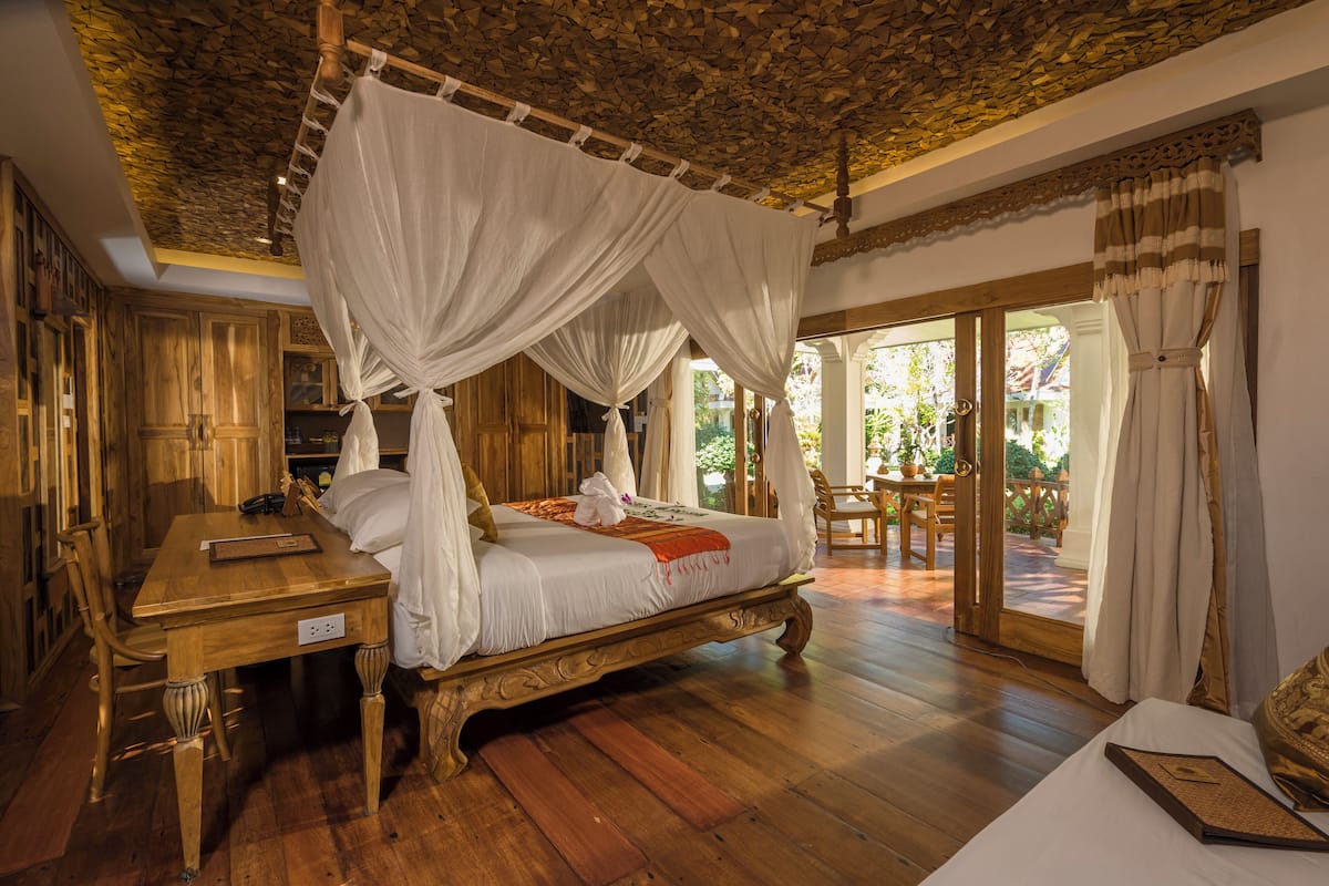 Um quarto amplo com cama de dossel, mobiliário de madeira e vista para o exterior.