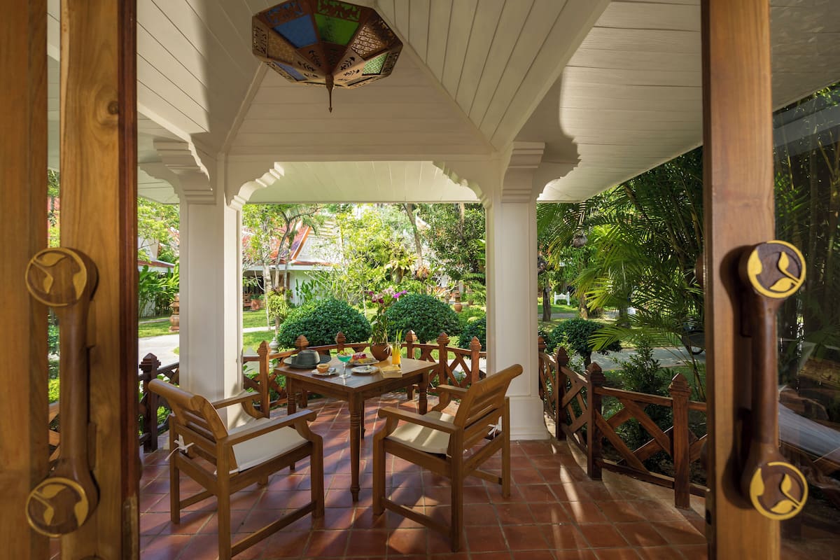 Estar amplo coberto com móveis de madeira e vista para um jardim exuberante.