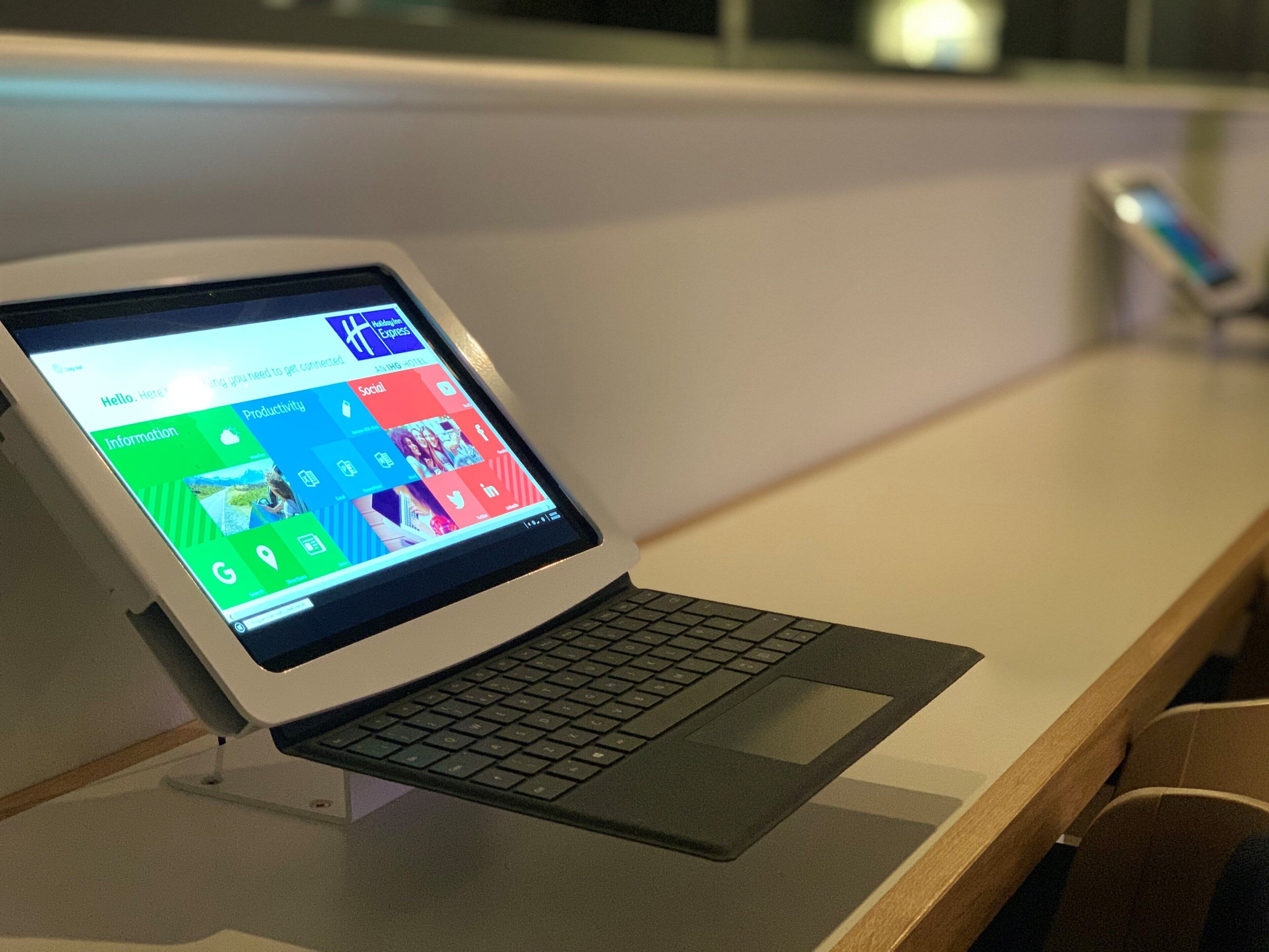 Um laptop sobre um suporte, com teclado conectado, exibindo uma interface de aplicativo colorida.