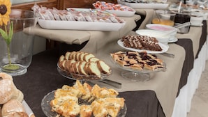 Uma mesa de buffet com diversos alimentos, incluindo pão, doces e sobremesas.