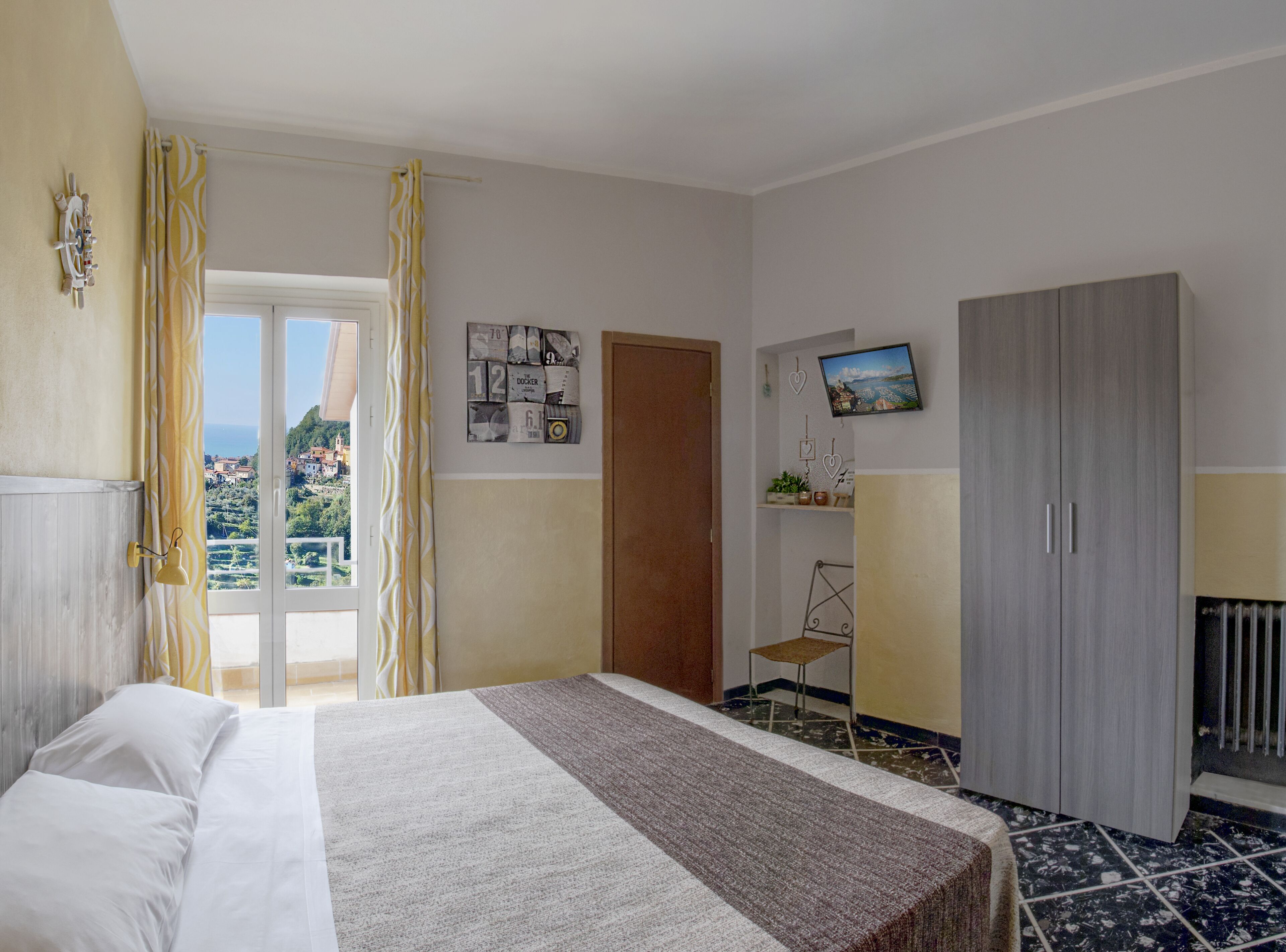 Quarto com cama, televisão, guarda-roupa e vista para o mar.