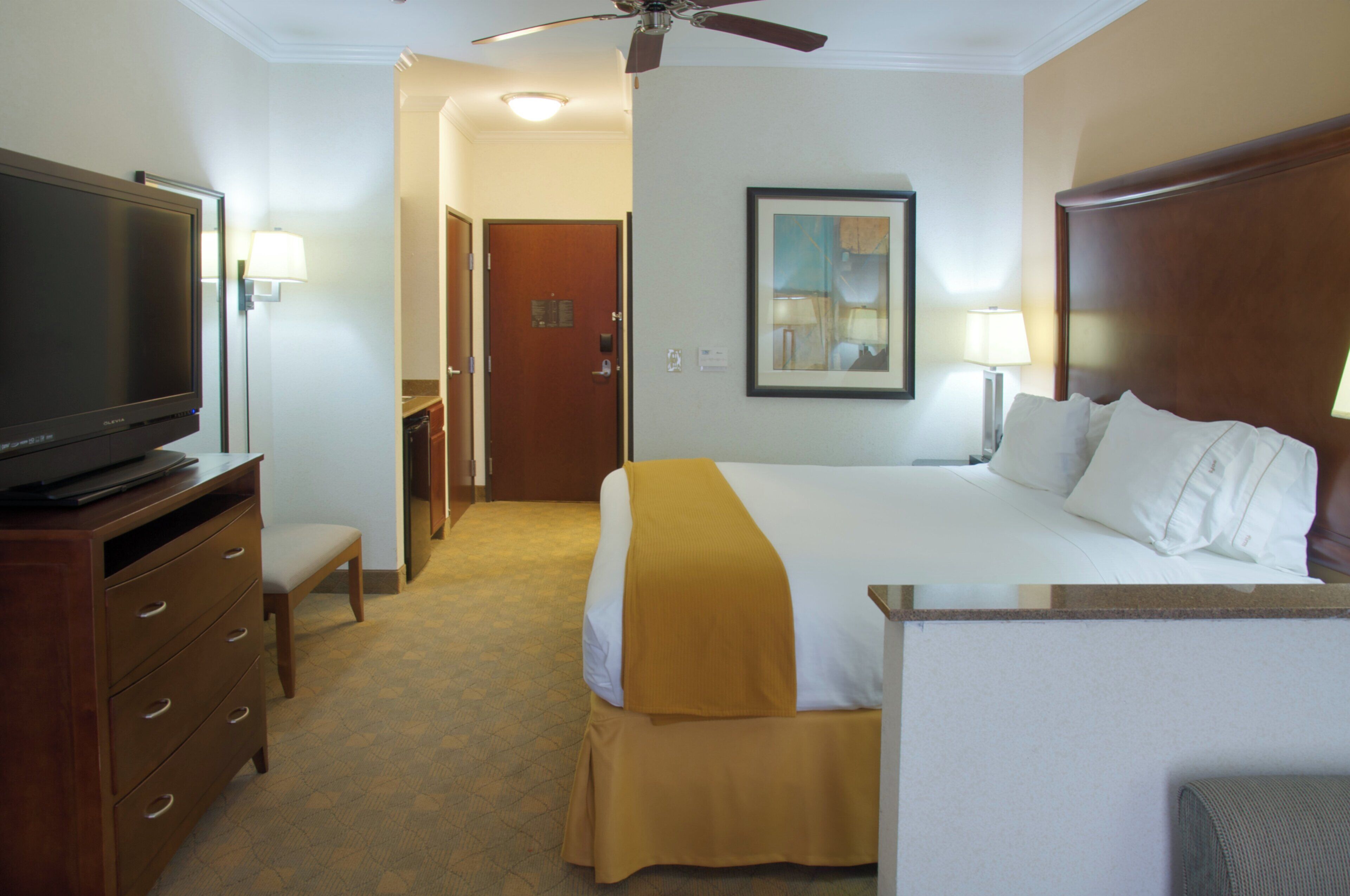 Quarto de hotel com uma cama, televisão, escrivaninha e uma cadeira.