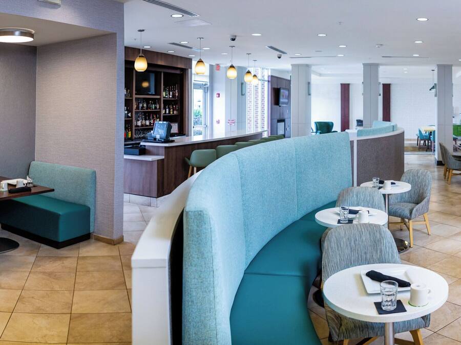 Restaurante moderno com assentos cor turquesa, área de bar e vista da cidade.