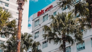 Um edifício de hotel com uma placa vermelha chamativa com a inscrição 'ibis HOTEL' e várias janelas.