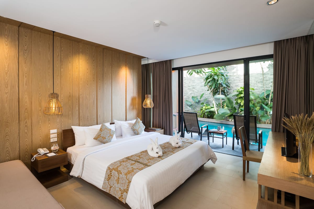 Quarto de hotel com uma cama grande, uma escrivaninha e vista para a área da piscina.