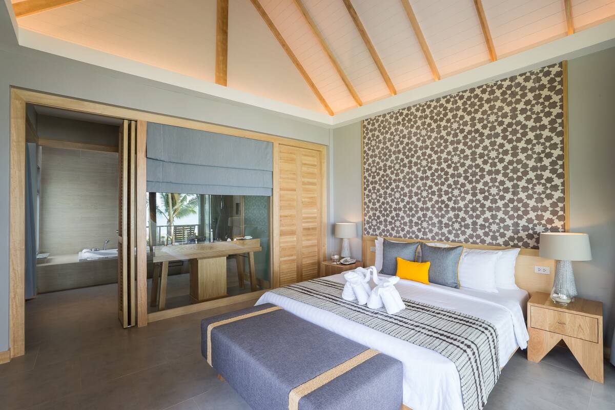 Quarto de hotel moderno com uma cama grande, uma escrivaninha e um banheiro com banheira.