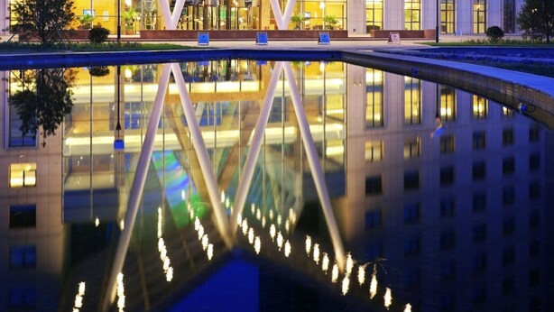 Um hotel moderno com fachada de vidro marcante e átrio central.