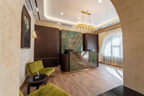 Uma área de recepção moderna com um balcão de mármore, um sofá verde e um candelabro.