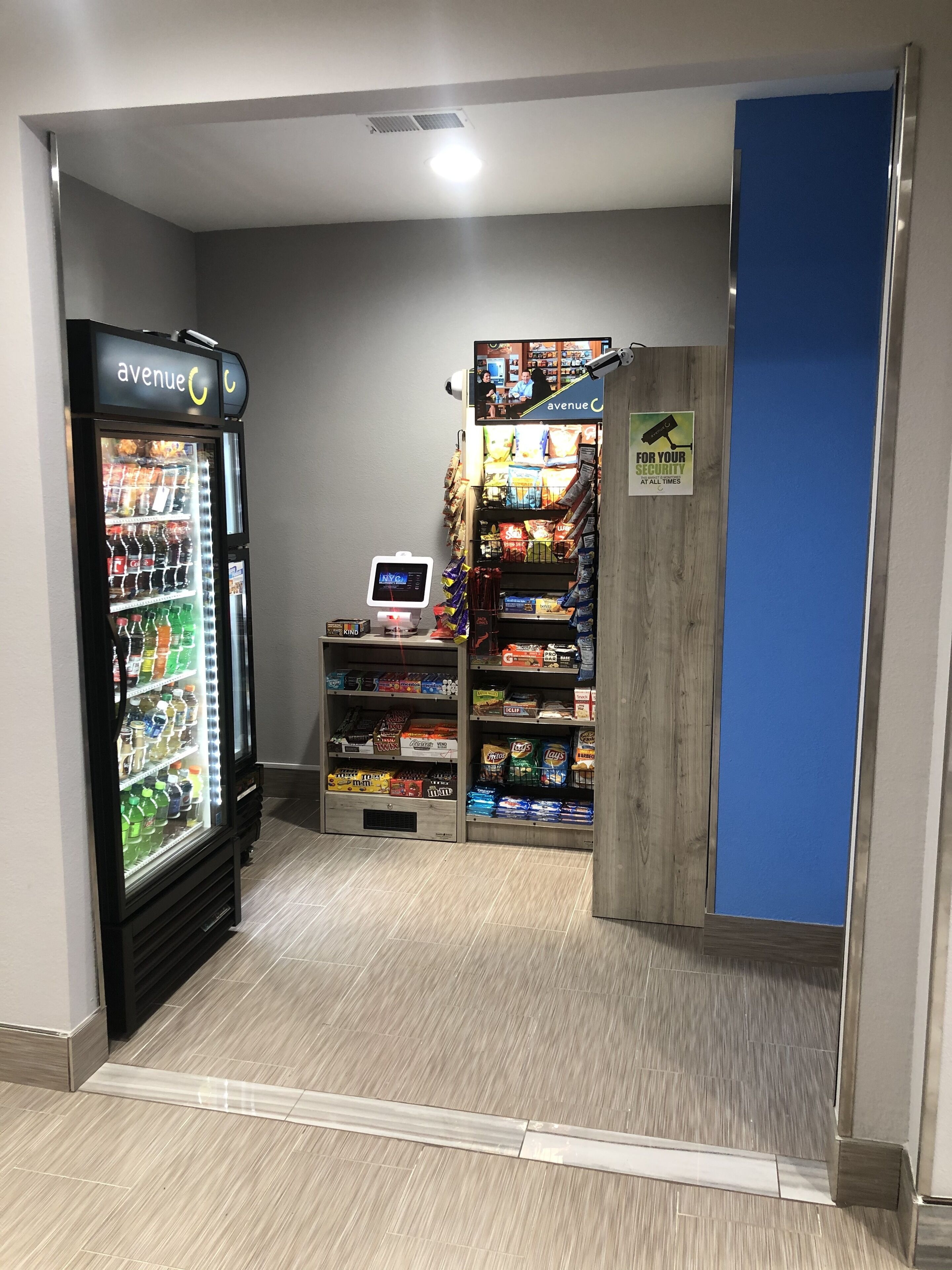 Uma área de máquinas de venda automática com um refrigerador e prateleiras repletas de lanches e bebidas.