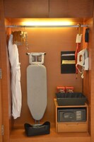 Quarto compacto com tábua de passar, micro-ondas e um pequeno armário.