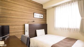 Quarto de hotel com painel de parede de madeira, cama com colcha branca e marrom, escrivaninha com televisão e telefone, e janela com cortinas.