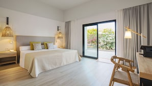 Quarto moderno com uma cama grande, mesas de cabeceira, uma cadeira de madeira e vista para o verde através de uma porta deslizante.