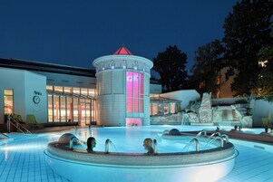 Uma piscina com área circular deofurôs, um recurso aquático e um edifício com estrutura em torre.